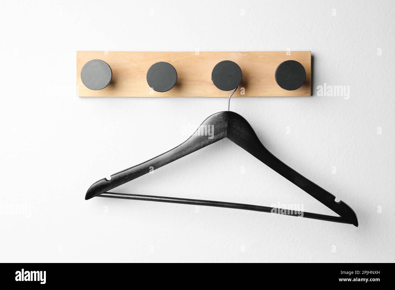 Rack with empty black clothes hanger on white wall Stock Photo - Alamy