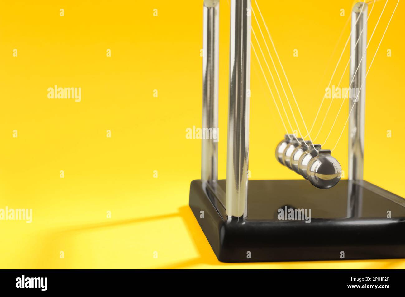 Newton's cradle on yellow background, space for text. Physics law of ...