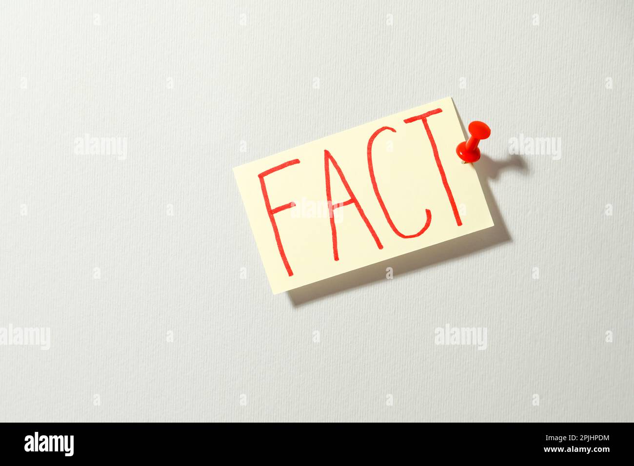 Sheet of paper with word Fact pinned to grey background, top view ...