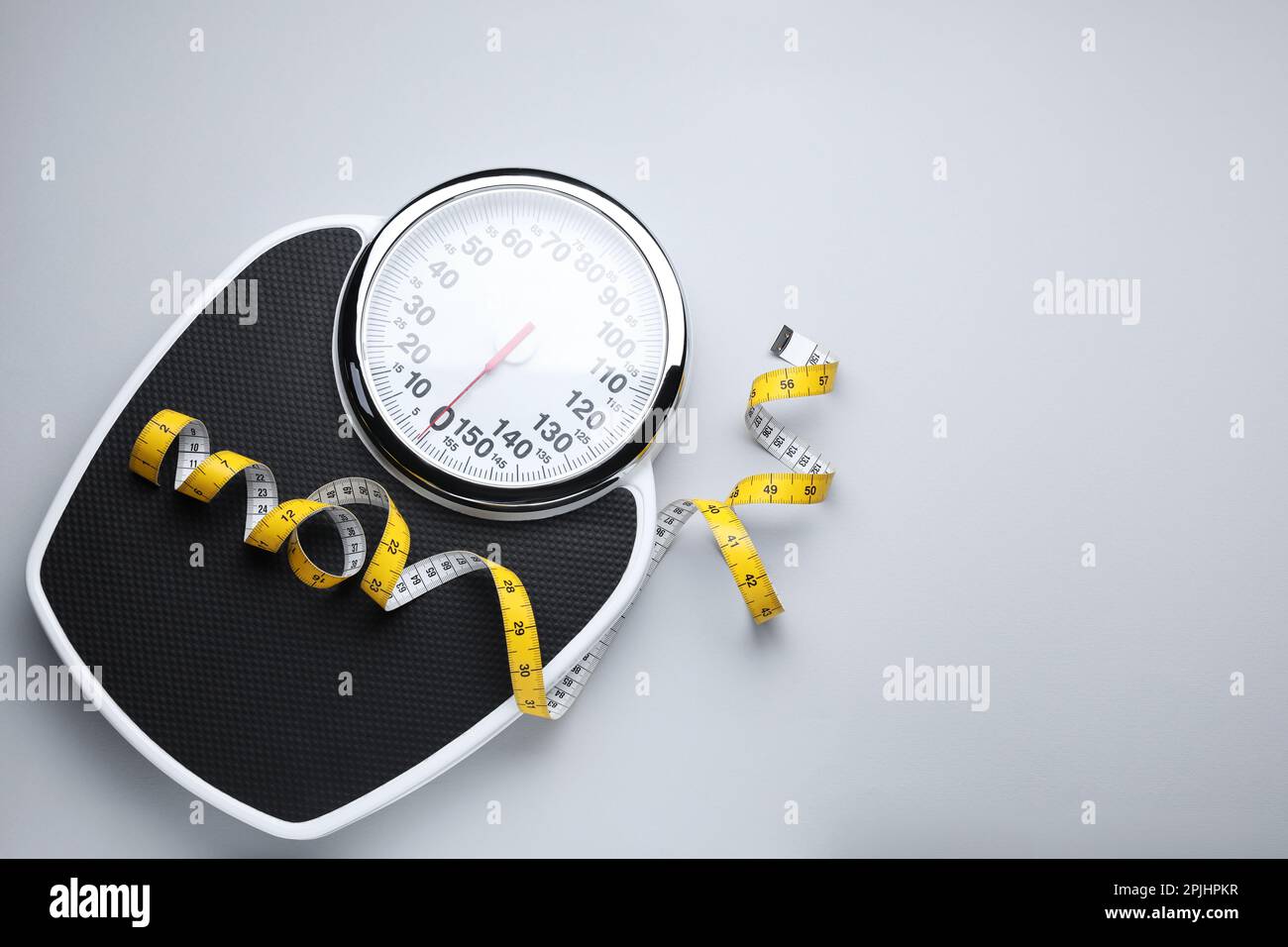 Scales and measuring tape on light grey background, top view. Space for ...