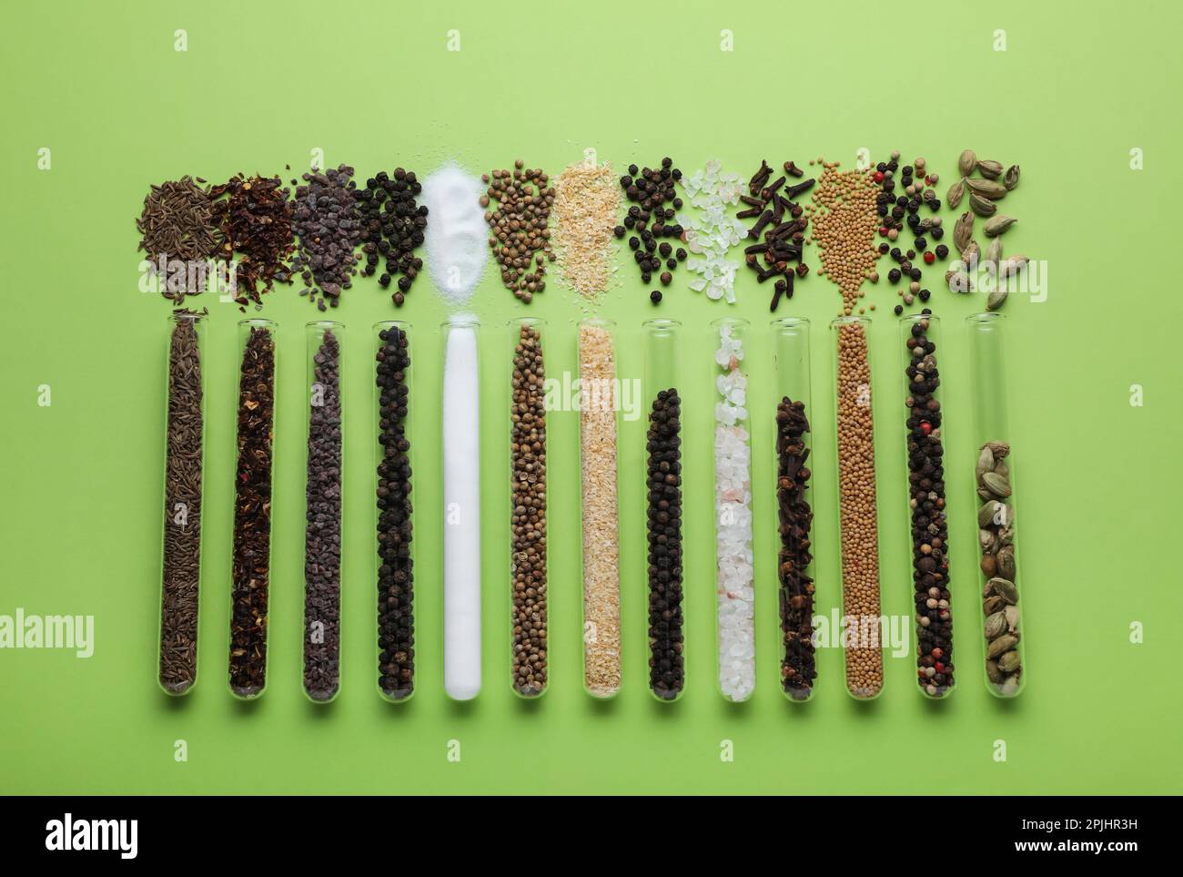 Test tubes with various spices on green background, flat lay Stock ...