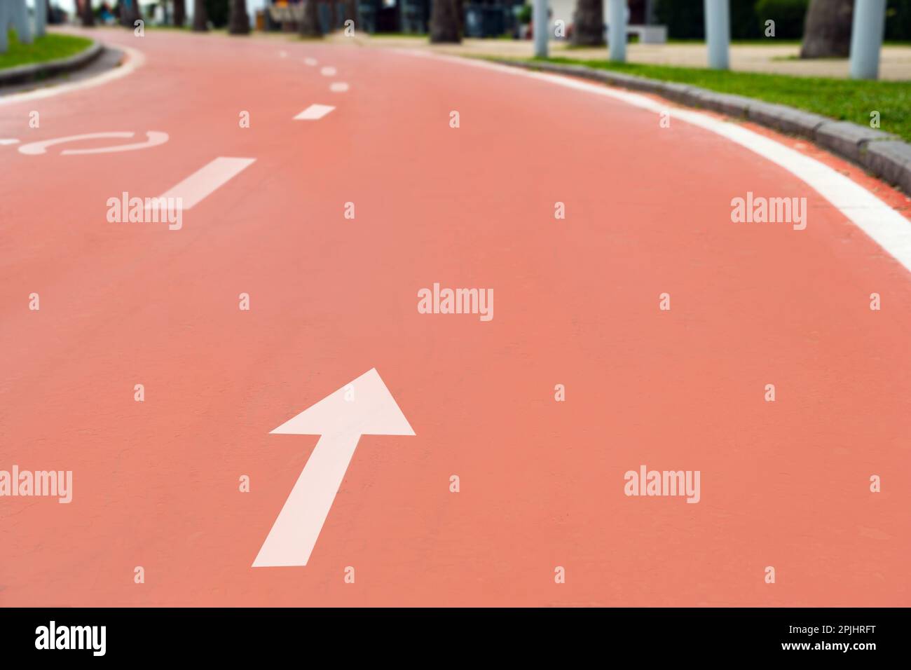 Red bike lane with painted white direction arrow Stock Photo - Alamy