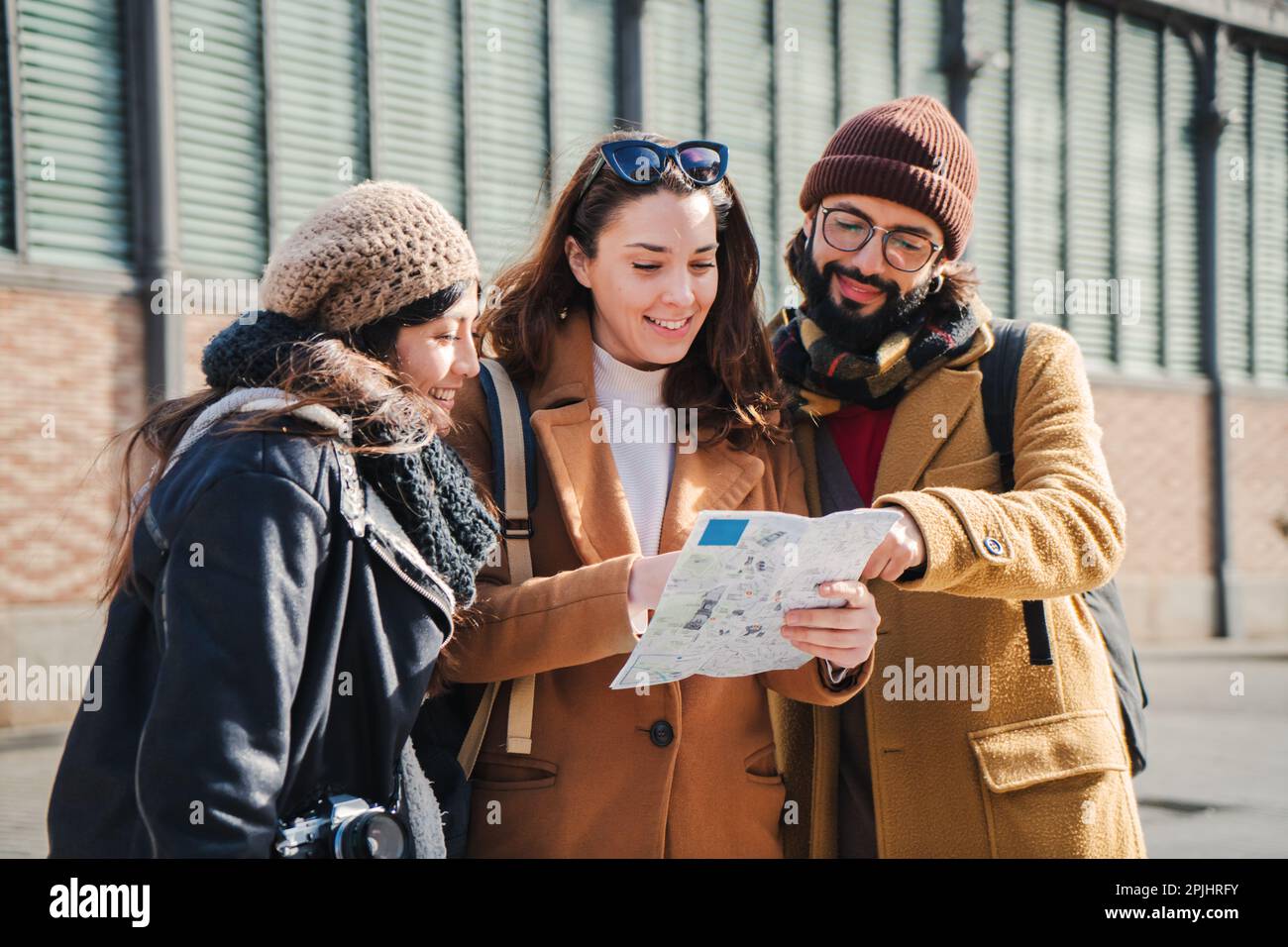 three tourist happy friends looking for directions on a map enjoying ...
