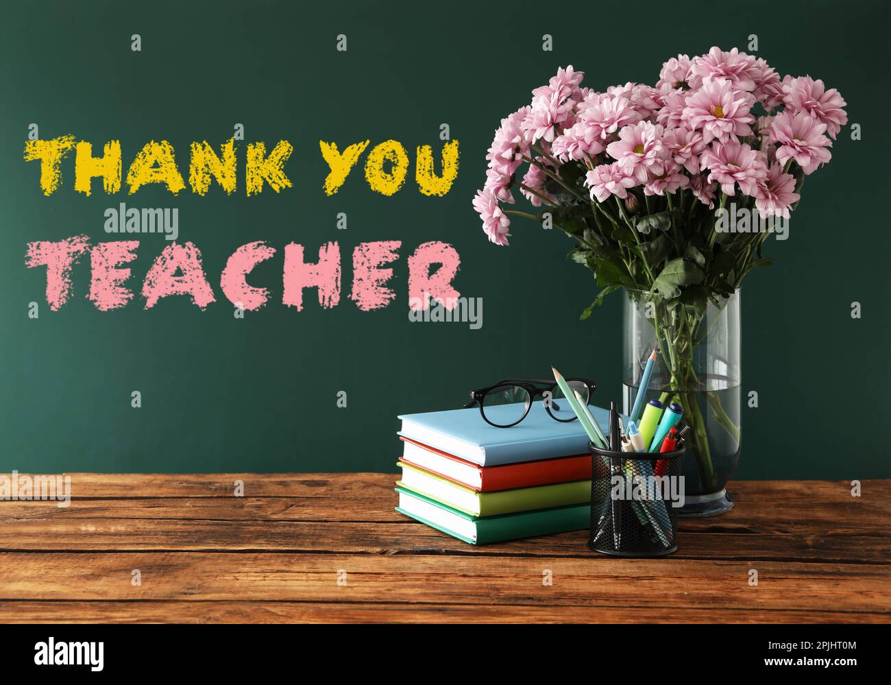 Set of stationery and flowers on wooden table near chalkboard with ...