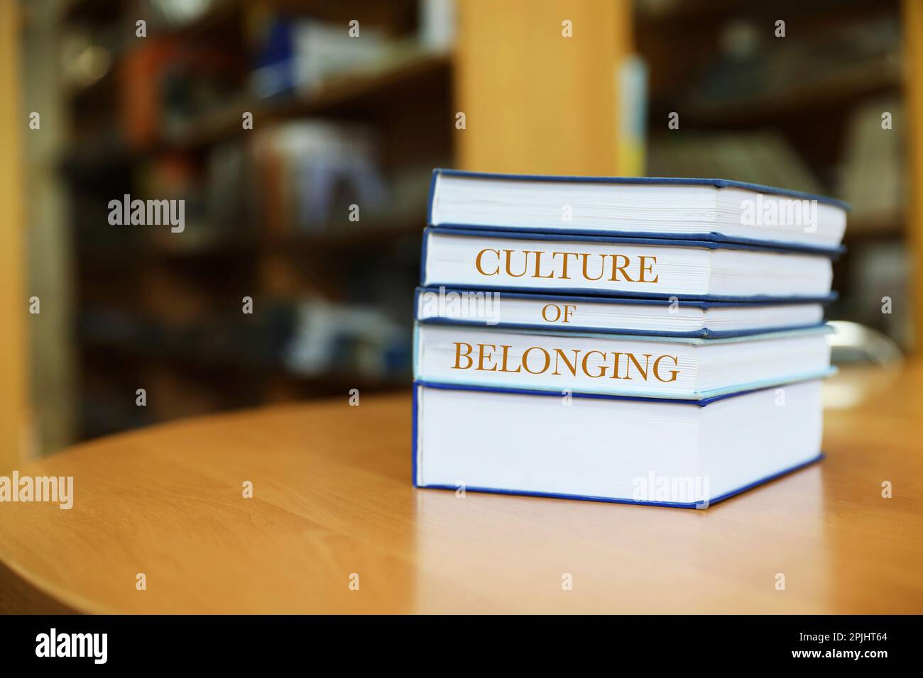 Stack of books with phrase Culture of Belonging on table in library ...