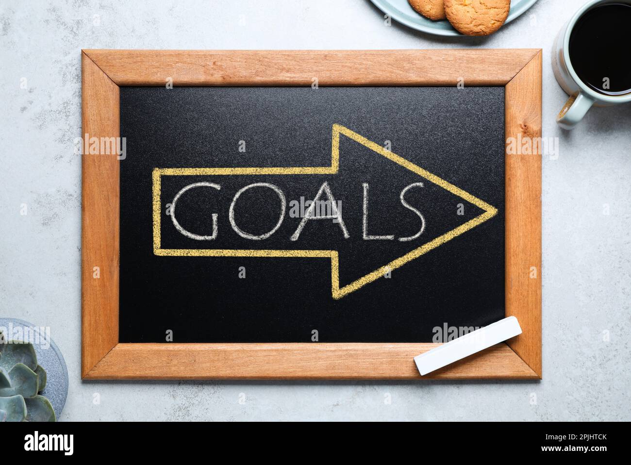 Blackboard with drawn arrow and word GOALS on light grey stone ...