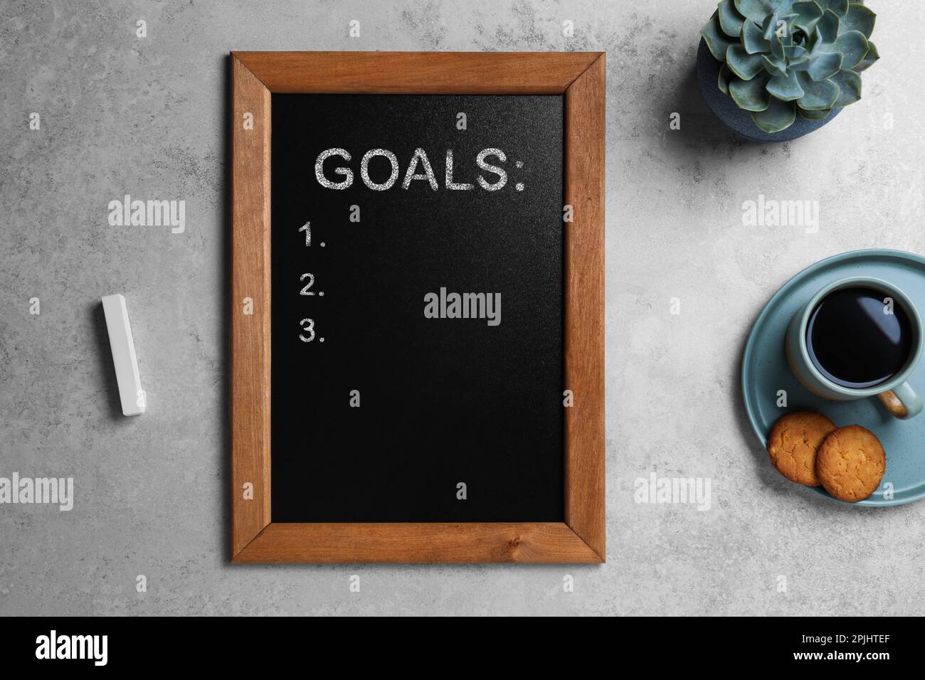 Blackboard with word GOALS and empty checklist on light grey stone ...
