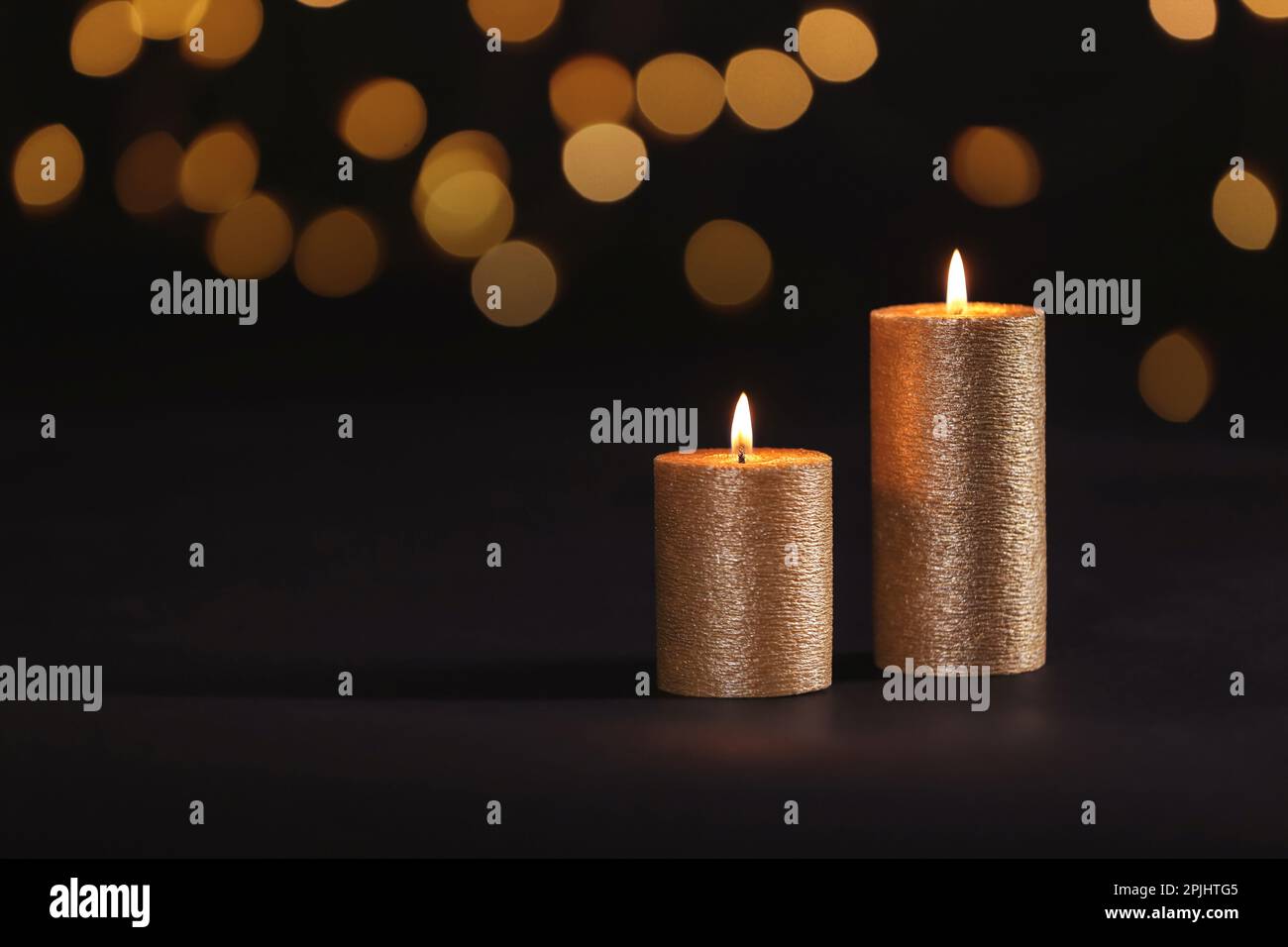 Burning gold candles on black background with blurred lights, bokeh ...