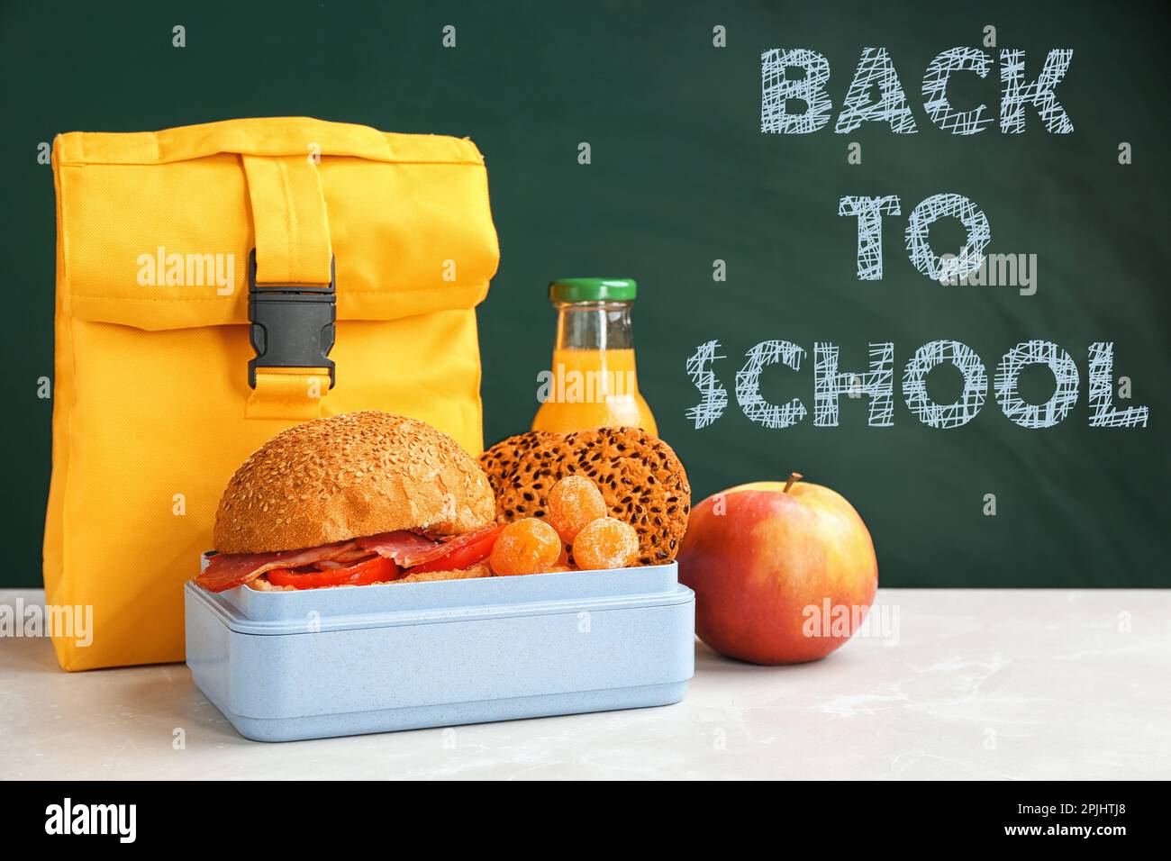 Lunch box with appetizing food and bag on table near chalkboard Stock ...