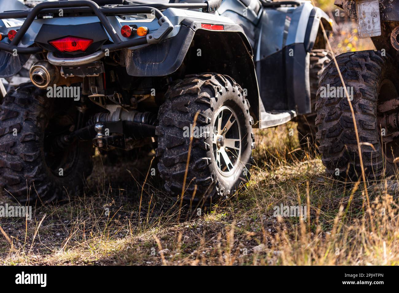 Close-up tail view of ATV quad bike on dirt country road. Dirty wheel ...