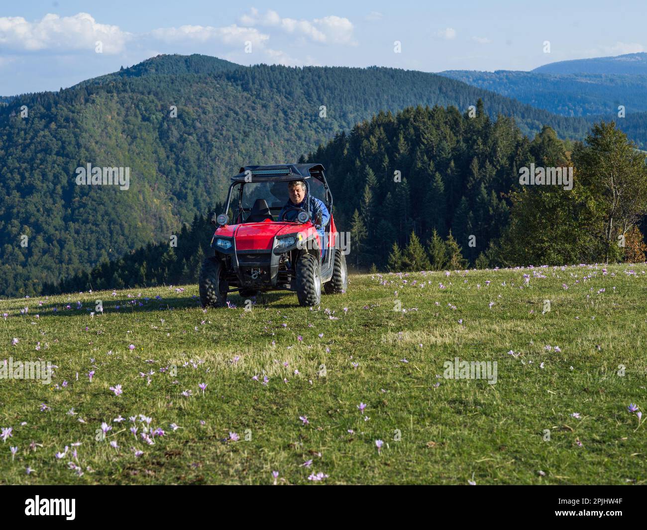 A man driving a quad ATV motorcycle through beautiful meadow landscapes Stock Photo - Alamy