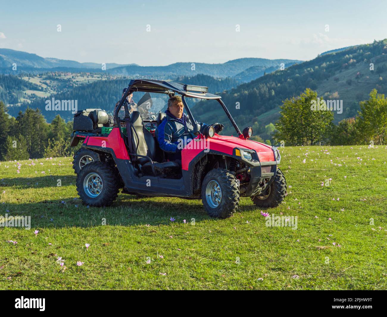 A man driving a quad ATV motorcycle through beautiful meadow landscapes Stock Photo - Alamy