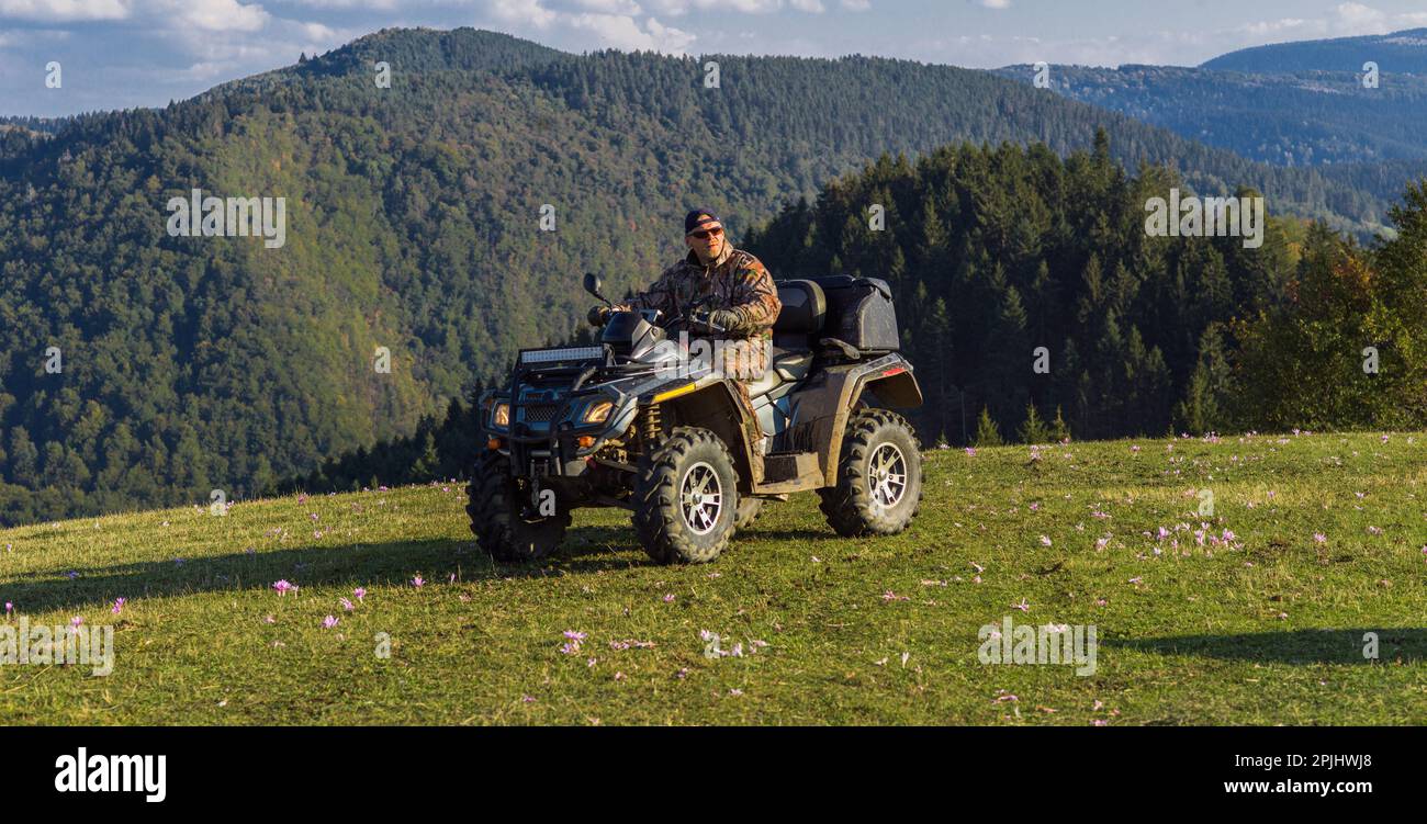 A man driving a quad ATV motorcycle through beautiful meadow landscapes Stock Photo - Alamy
