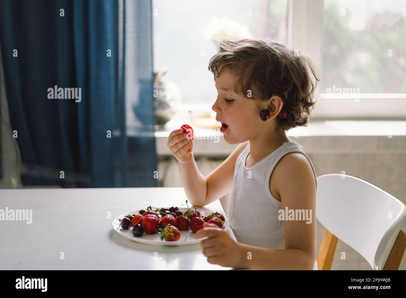 Cute beautiful little boy eating fresh cherry and strawberry Stock ...