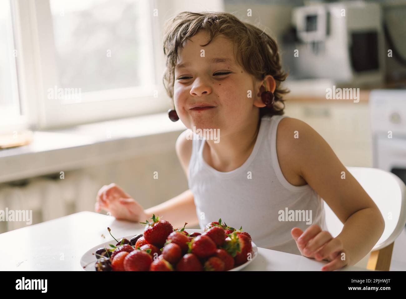 Cute beautiful little boy eating fresh cherry and strawberry Stock ...