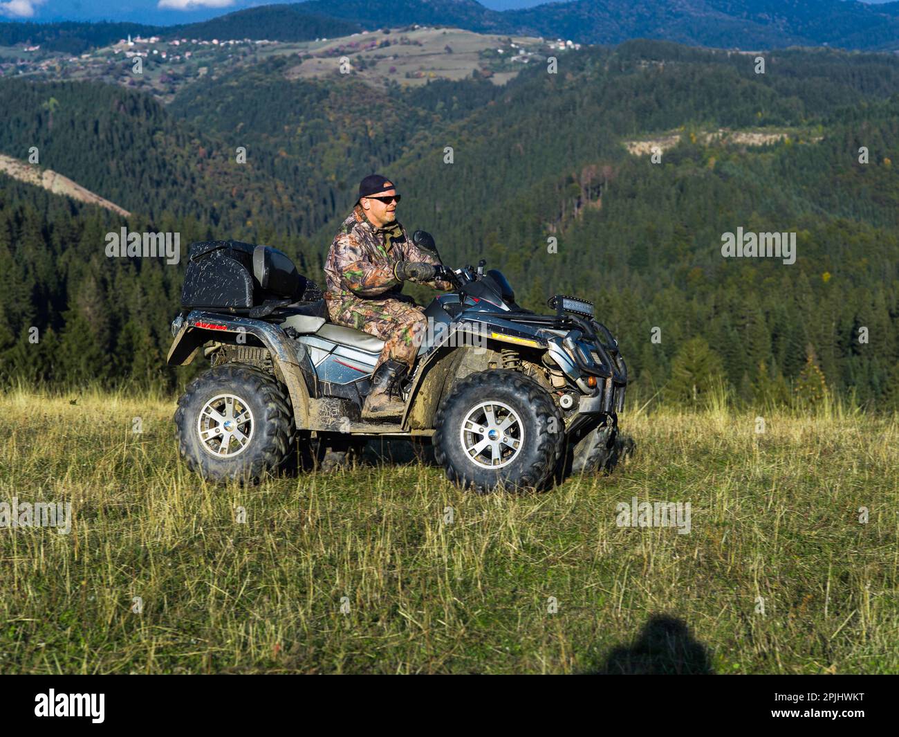 A man driving a quad ATV motorcycle through beautiful meadow landscapes Stock Photo - Alamy