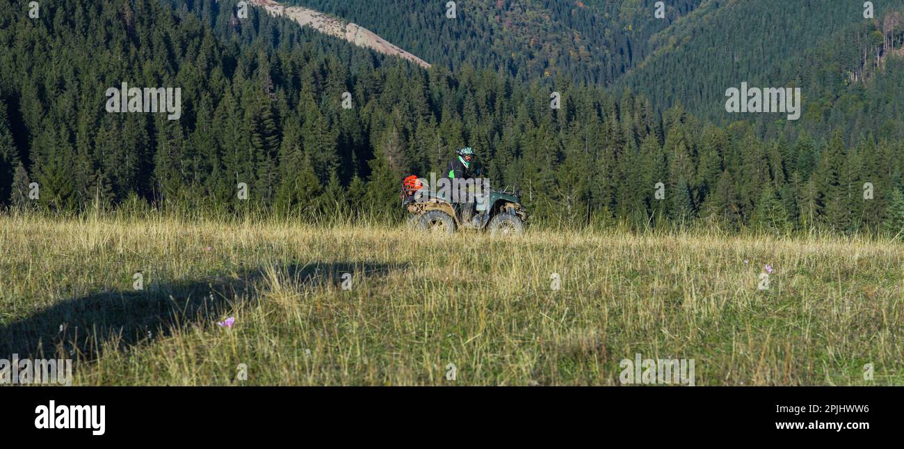 A man driving a quad ATV motorcycle through beautiful meadow landscapes Stock Photo - Alamy