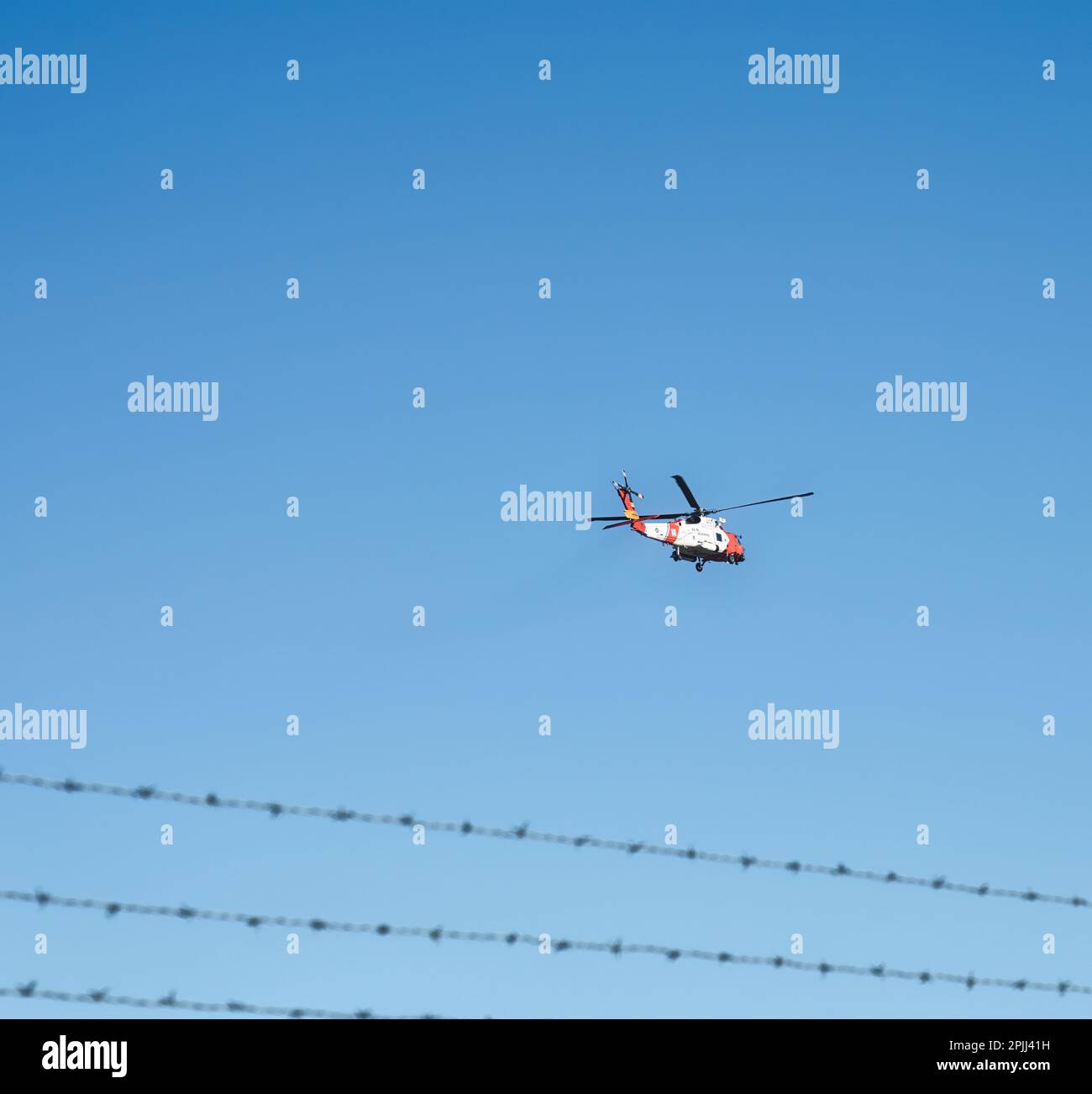 Coast Guard helicopter leaving a secure area with a chain link fence ...