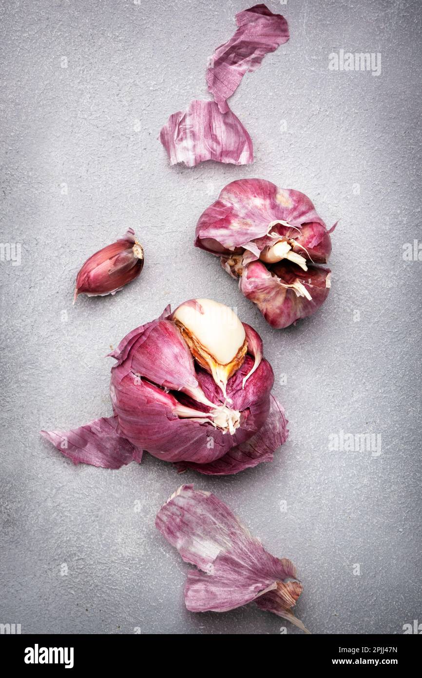 Fresh purple garlic with husk on gray kitchen table background, top ...
