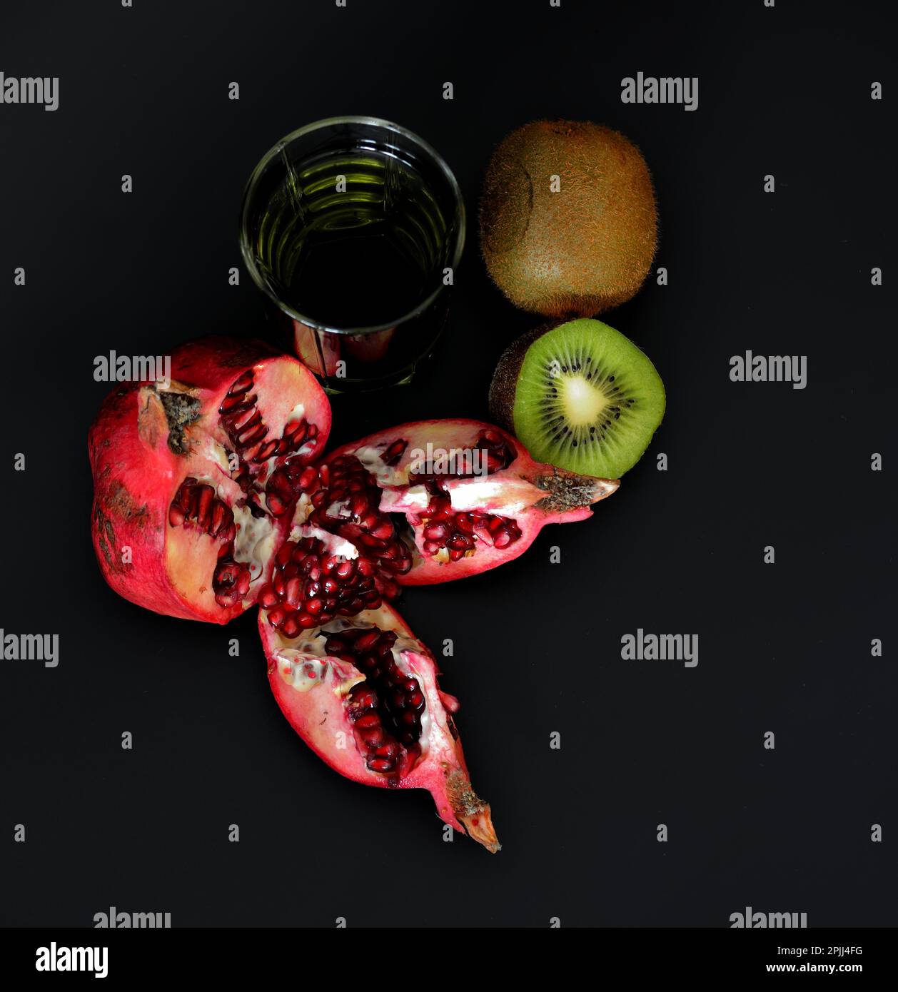 A tall glass glass of fruit juice on a black background, next to a ripe ...