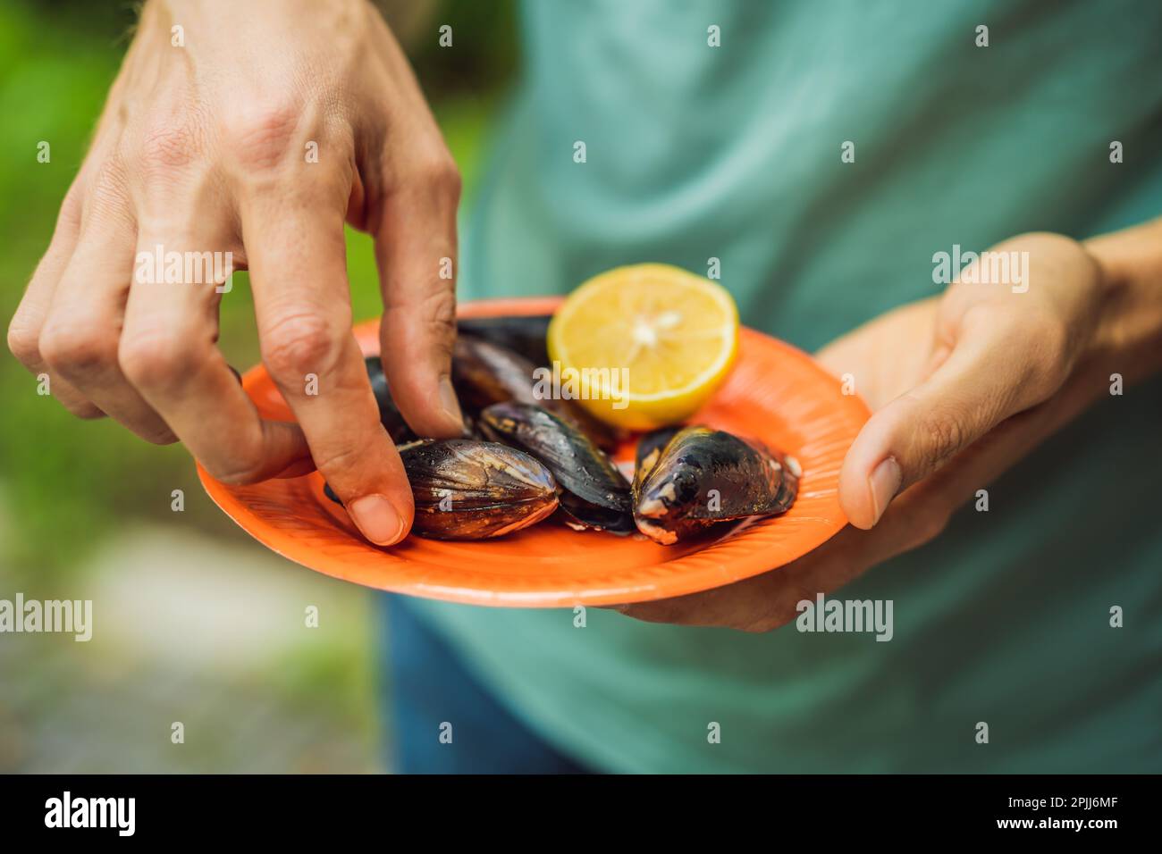 Heap of mussels in shells stuffed with rice. Man is going to eat midye ...