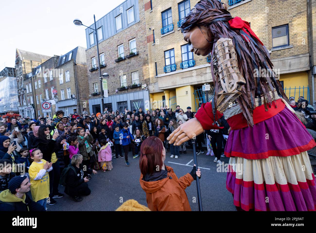 London, UK. 02nd Apr, 2023. Little Amal dances with a child during her ...