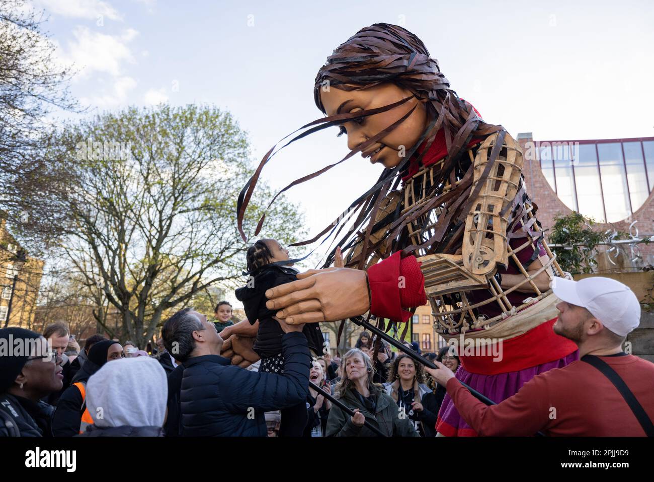 London, UK. 02nd Apr, 2023. Little Amal hugs a child during her walk in ...