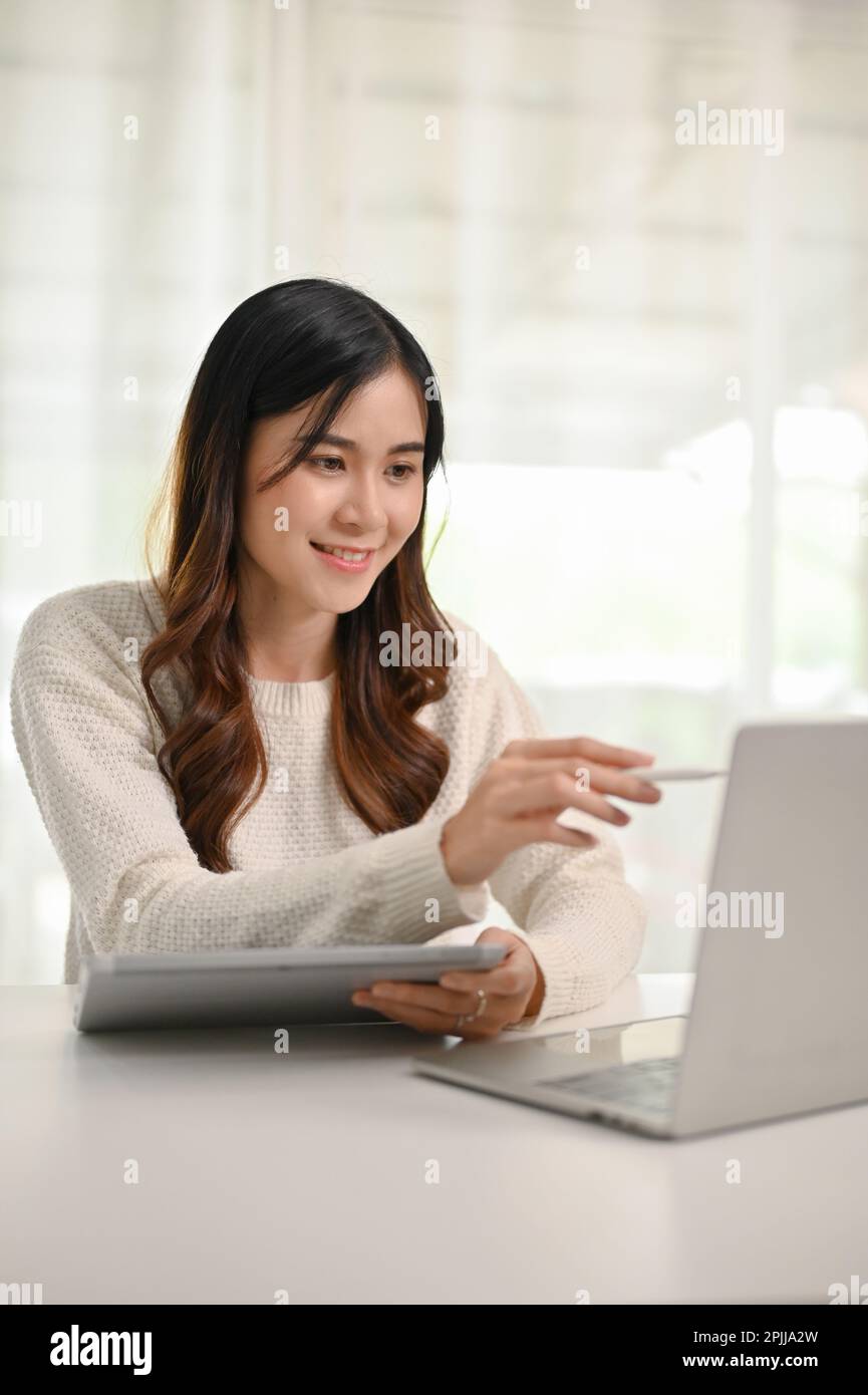Portrait of a beautiful charming young Asian woman pointing pen at a ...