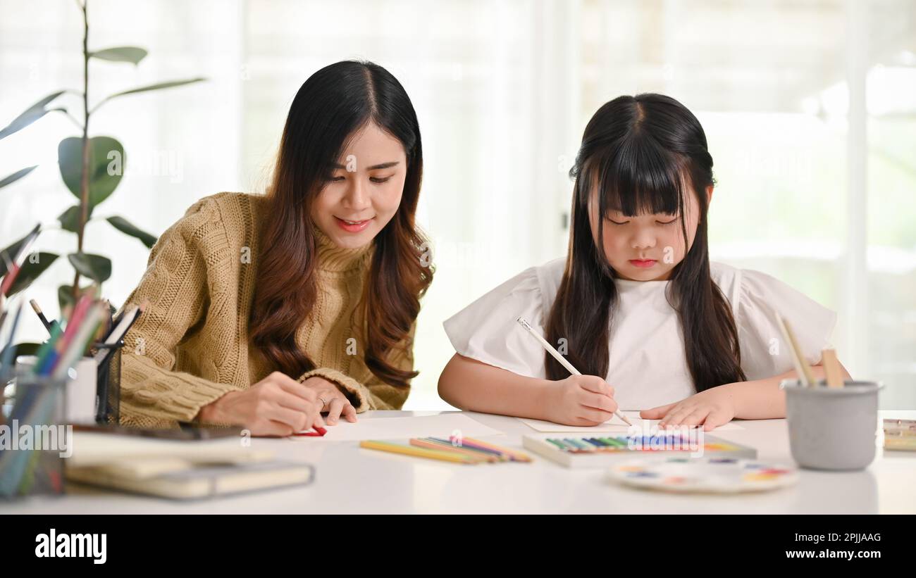 Attractive and caring young Asian sister helping her little sister to ...