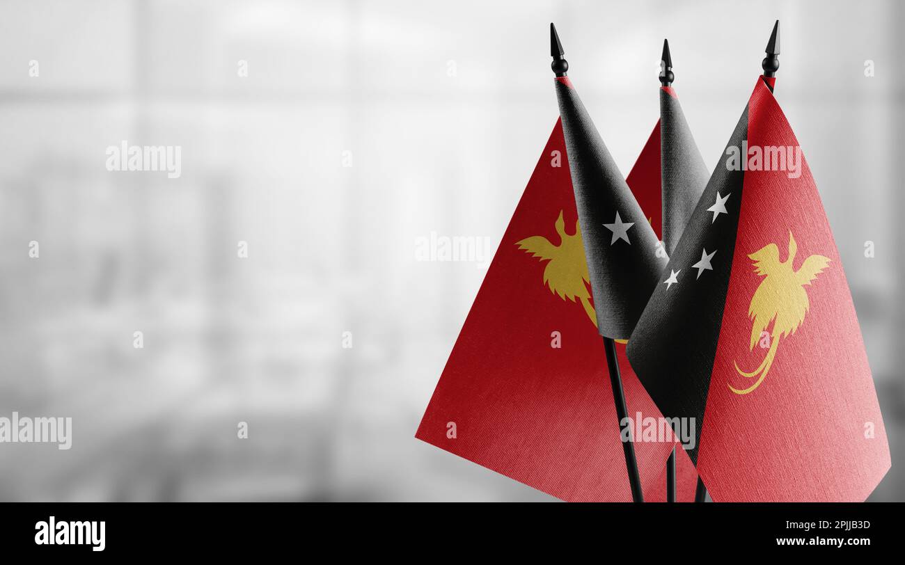 Small flags of the Papua New Guinea on an abstract blurry background ...