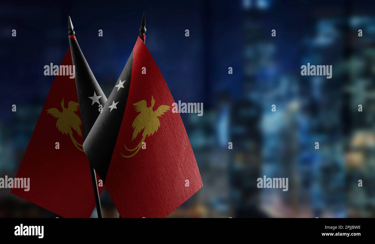 Small flags of the Papua New Guinea on an abstract blurry background ...