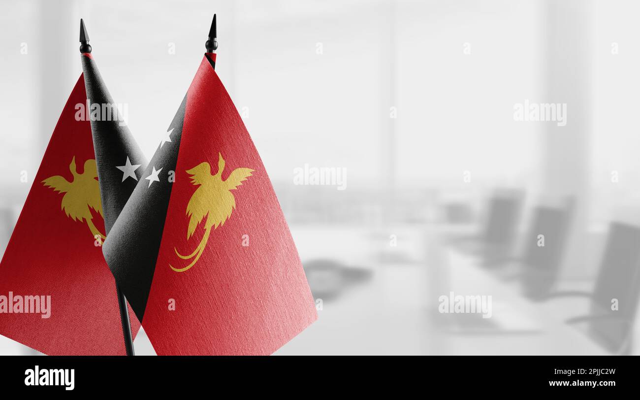 Small flags of the Papua New Guinea on an abstract blurry background ...