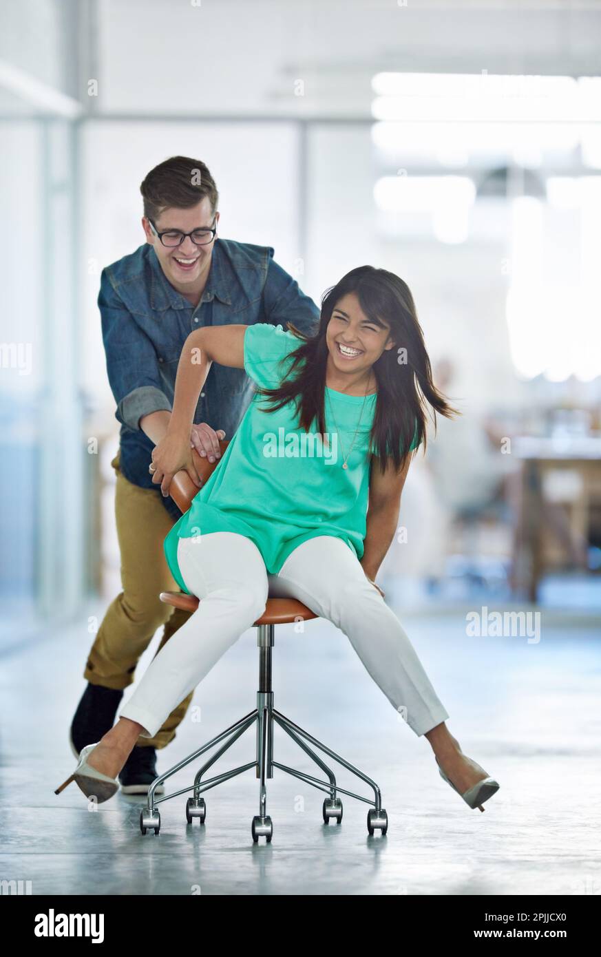 Office fun. a male coworker pushing his female coworker around an ...