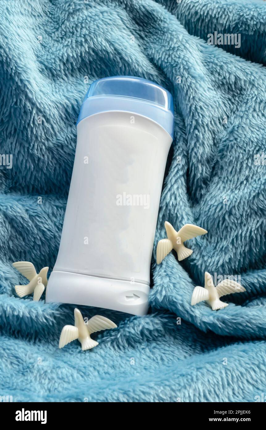 A white antiperspirant bottle with blue cap and four ornamentl doves ...