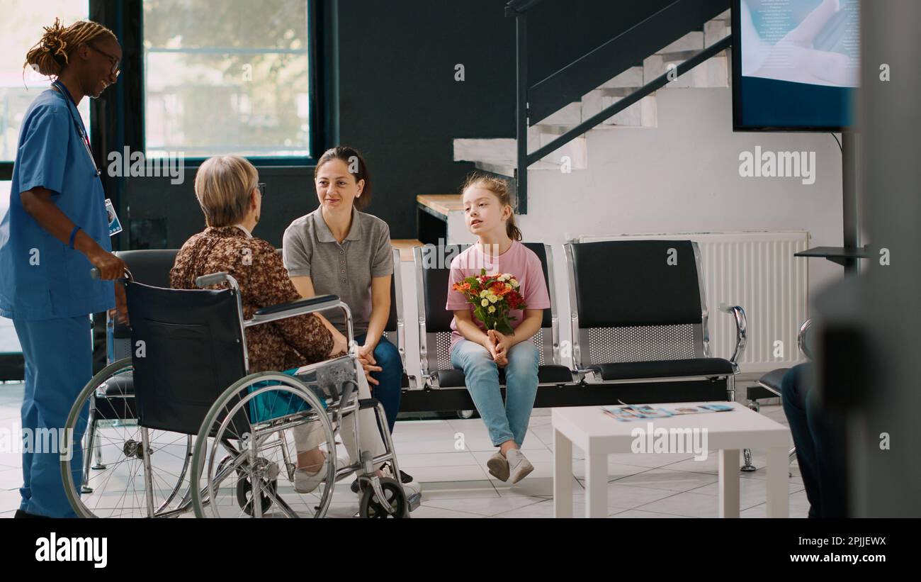 Elderly patient in wheelchair meeting with family in hospital waiting ...