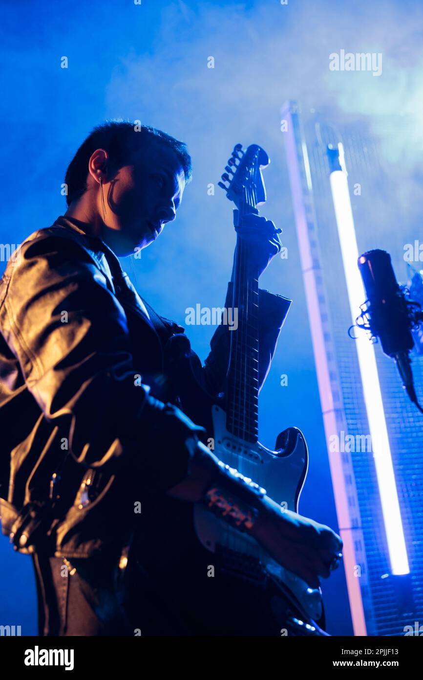 Brunette rockstar with short hair holding electric guitar playing rock ...