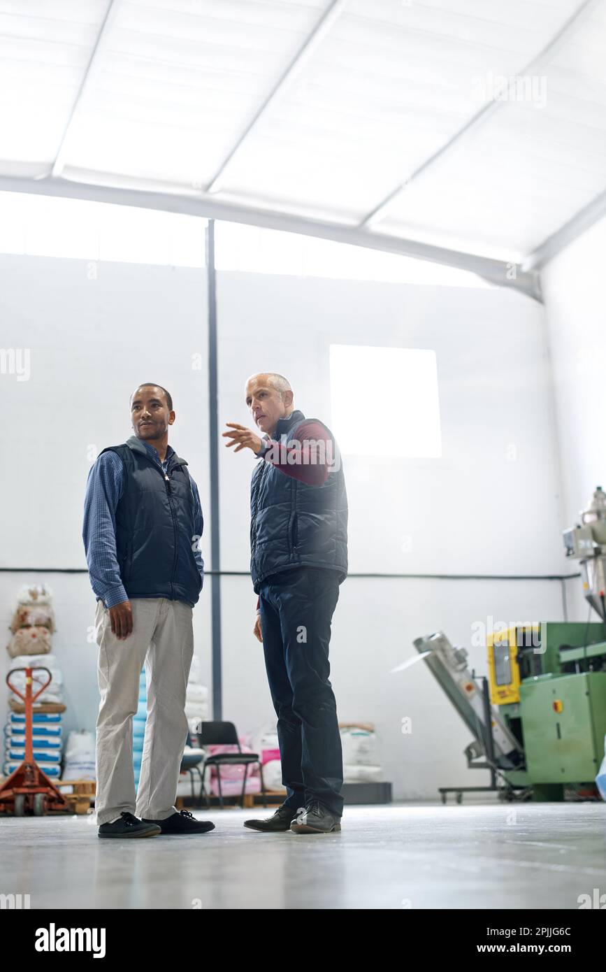 Discussing operations on the factory floor. two factory managers doing ...