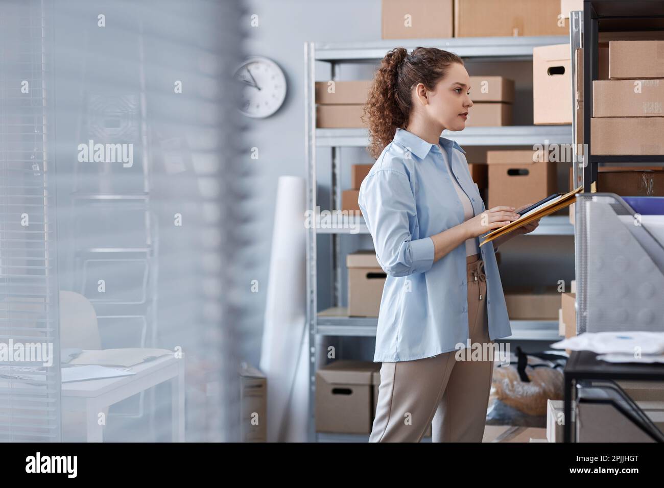 Young female manager with tablet and documents standing in front of ...
