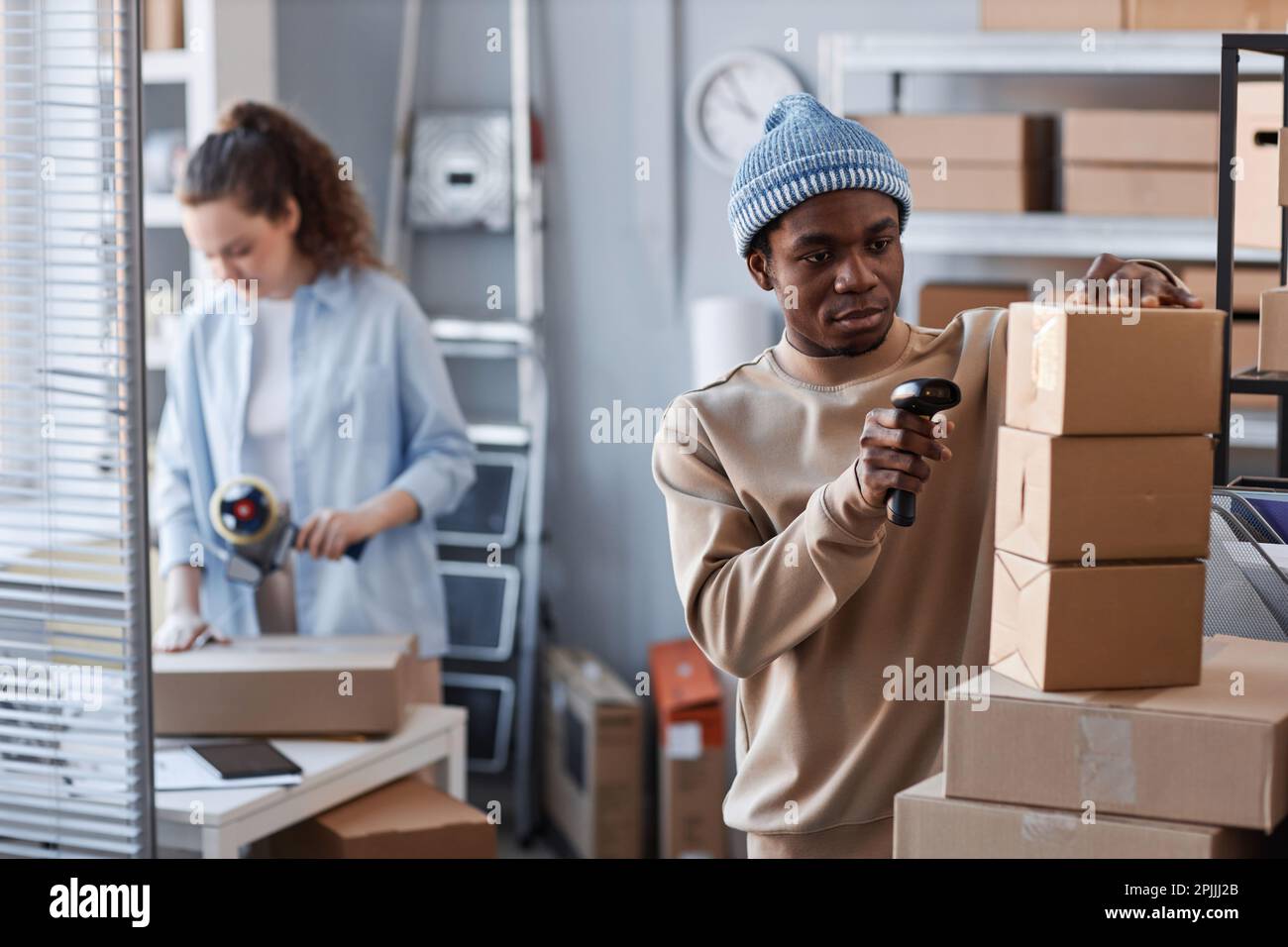 African American male worker of storage room scanning codes on boxes ...
