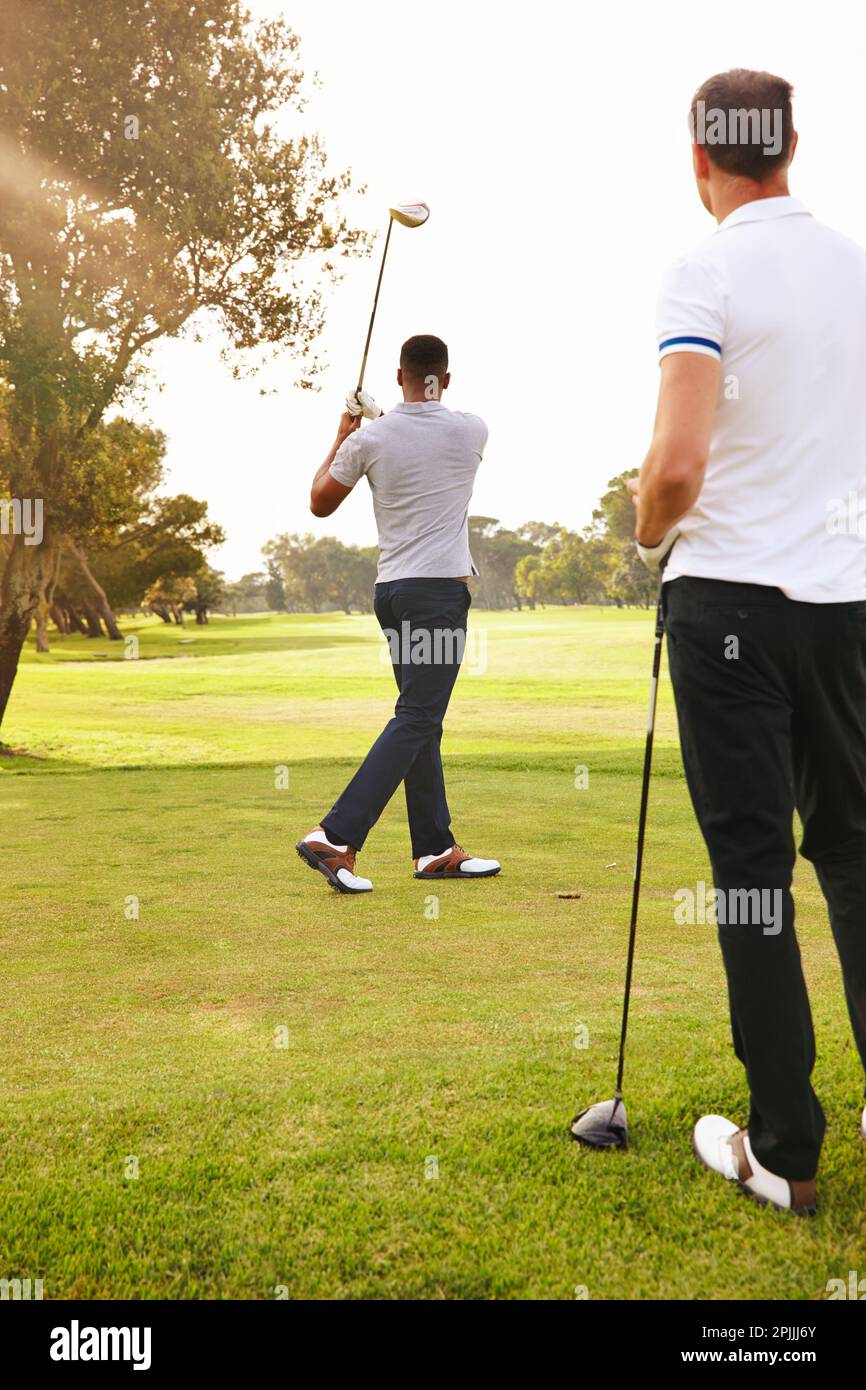 Hitting that dream drive. Rear view shot of two men playing a game of ...