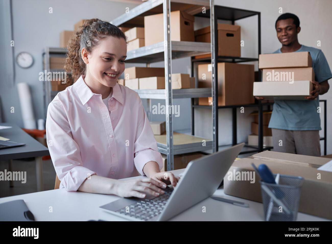 Happy young woman typing on laptop keyboard while African American man ...