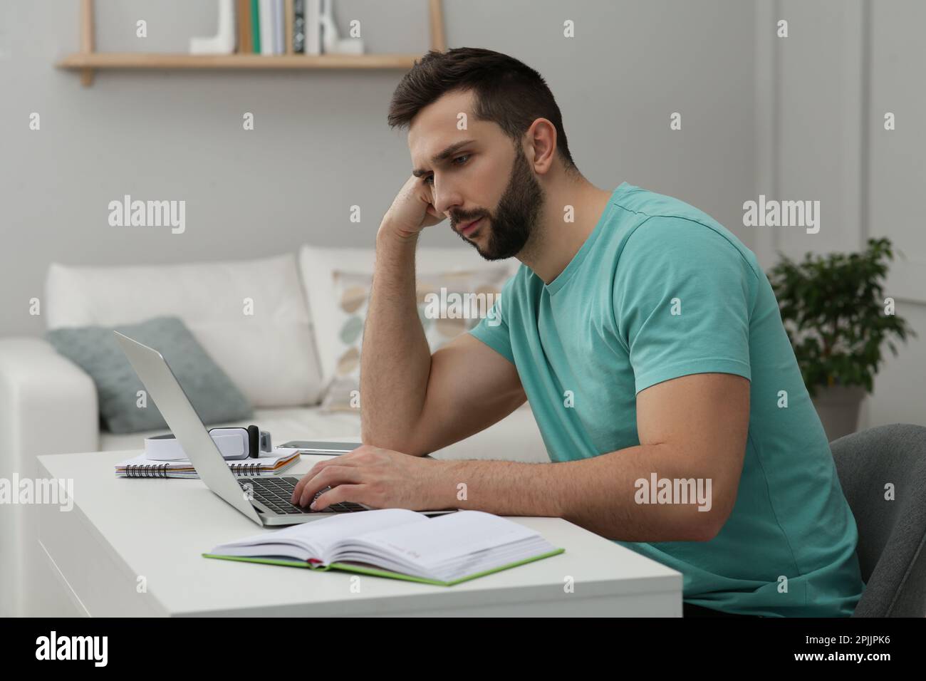 Online test. Man studying with laptop at home Stock Photo - Alamy