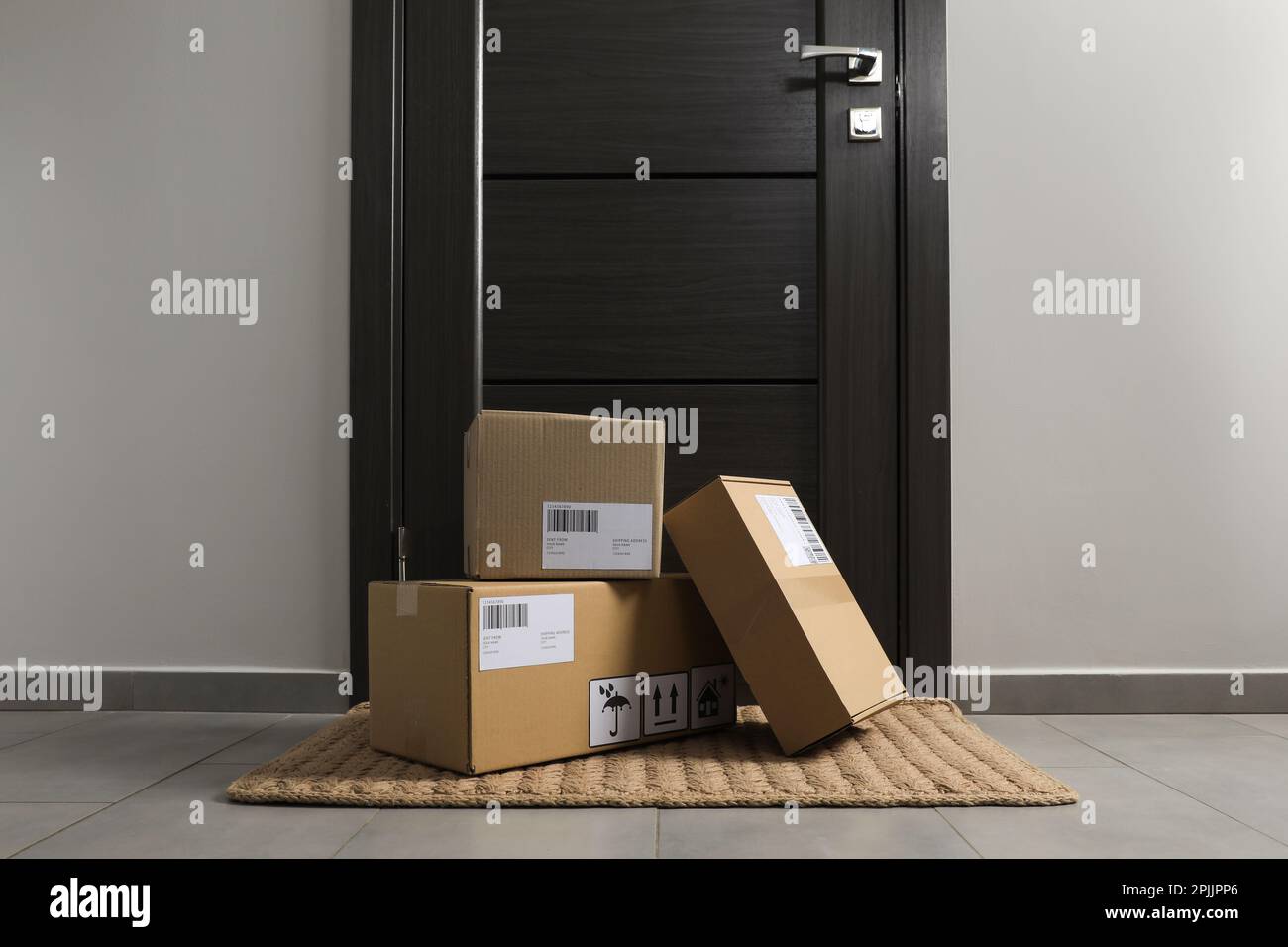 Cardboard boxes on floor mat near entrance. Parcel delivery service ...