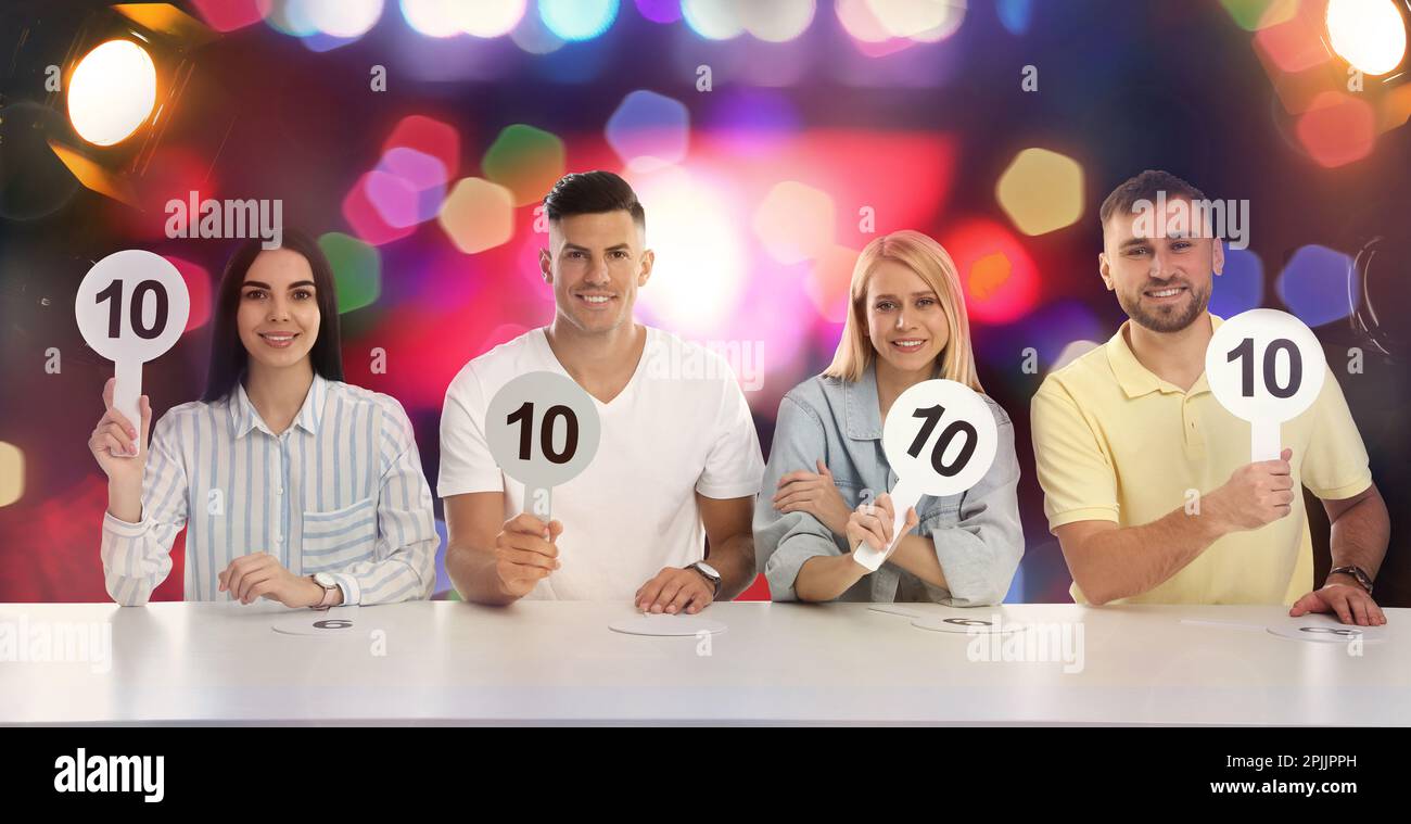 Panel of judges holding signs with highest score at table against ...