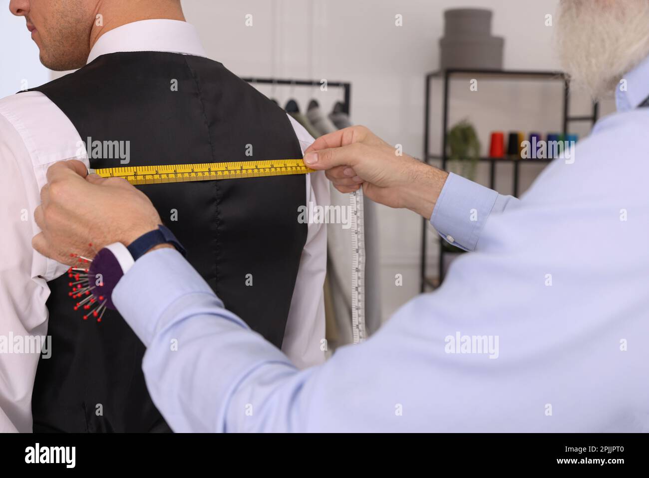 Professional tailor measuring client's back width in atelier, closeup ...
