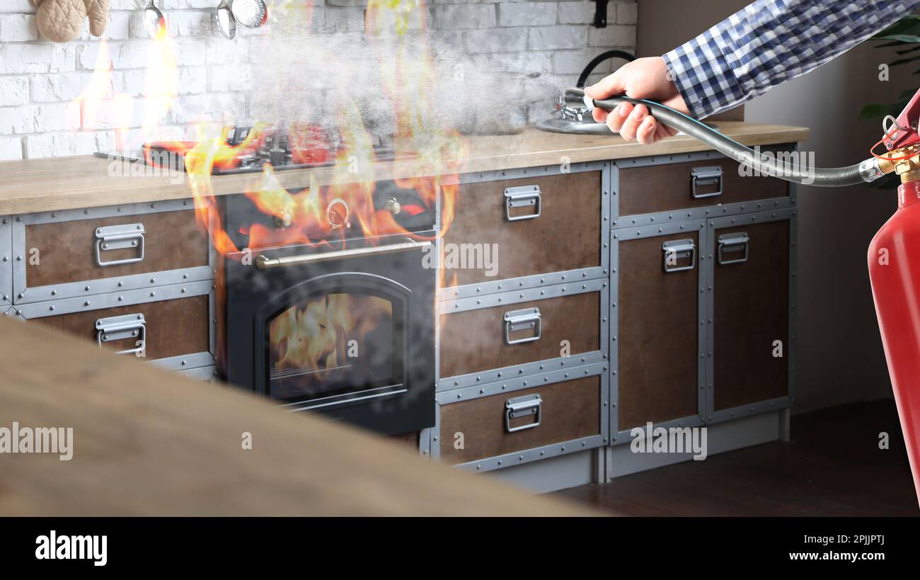 Man putting out burning stove and oven with fire extinguisher in ...