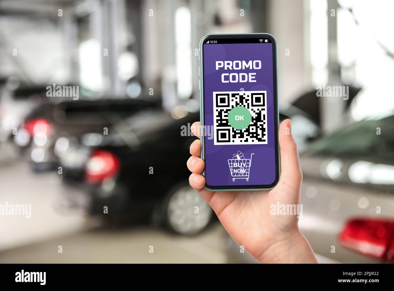 Woman holding smartphone with activated promo code in car dealership ...