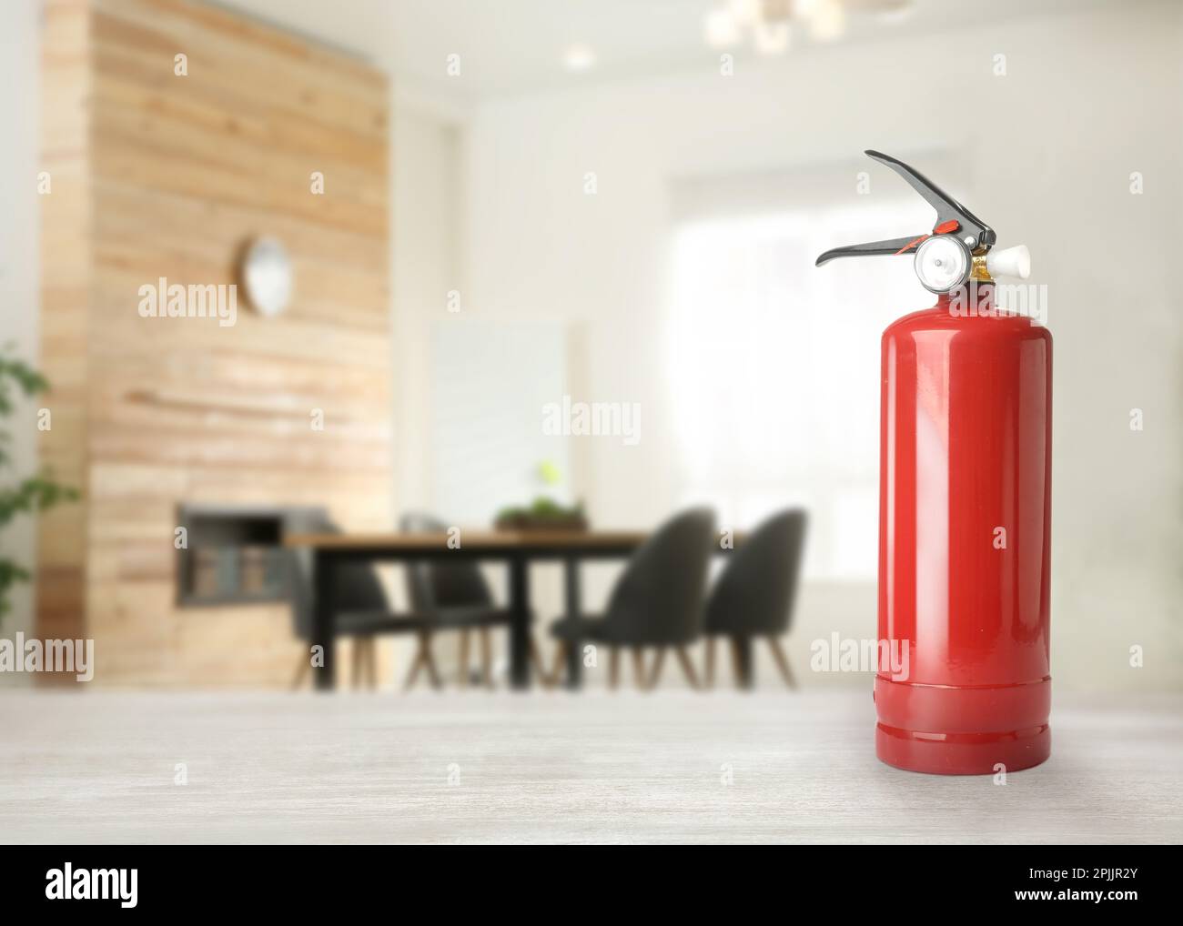 Fire extinguisher on white wooden table in room. Space for text Stock ...