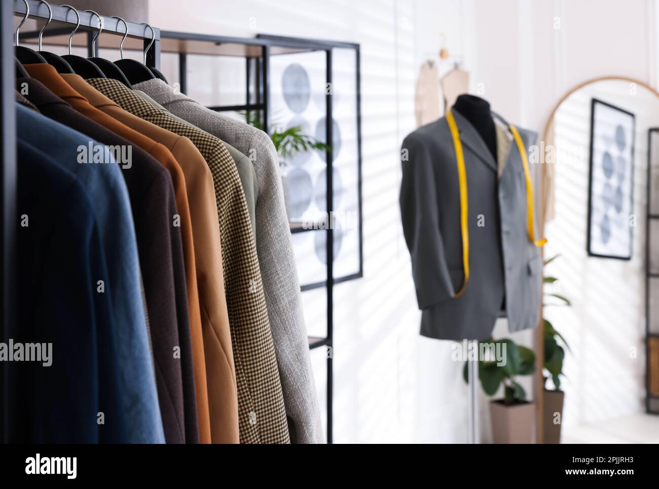 Rack with male suits and mannequin in tailor shop Stock Photo - Alamy