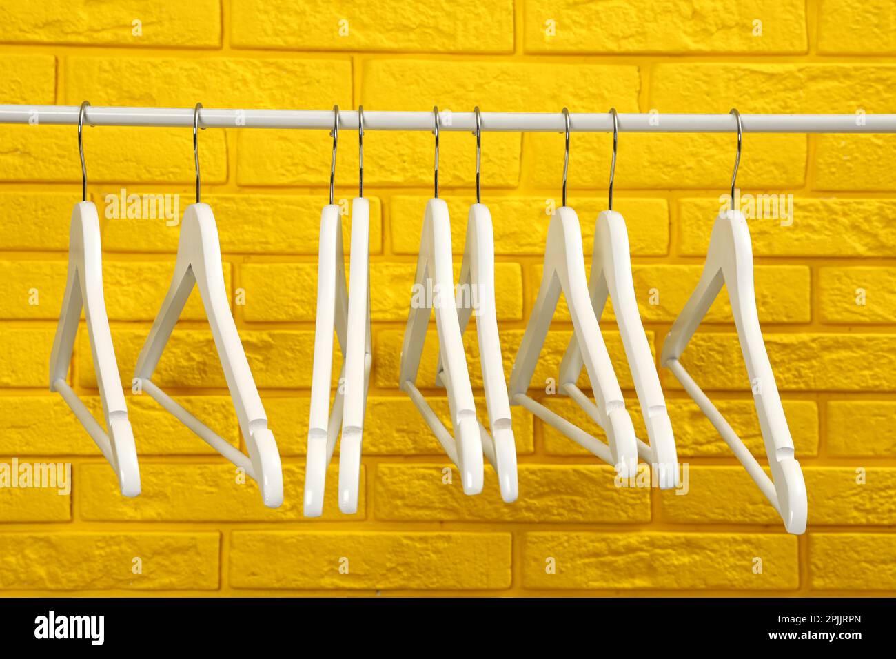 Wardrobe rack with many hangers near yellow brick wall Stock Photo - Alamy